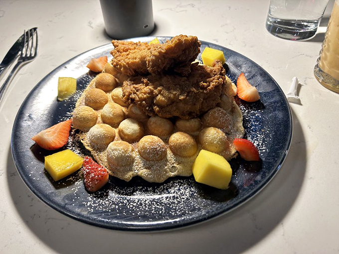 Brunch reimagined: Crispy fried chicken perched atop golden bubble waffles with fresh fruit&mdash;a dish that makes morning people out of night owls.