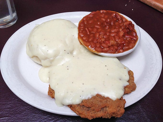 Behold the chicken fried steak in its natural habitat&mdash;swimming in creamy gravy with baked beans standing by for moral support.