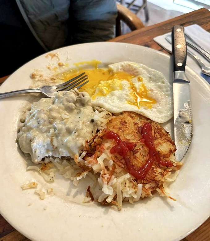 Behold the holy trinity of breakfast perfection: crispy hash browns, sunny-side-up eggs, and country gravy that could make a vegetarian reconsider their life choices.