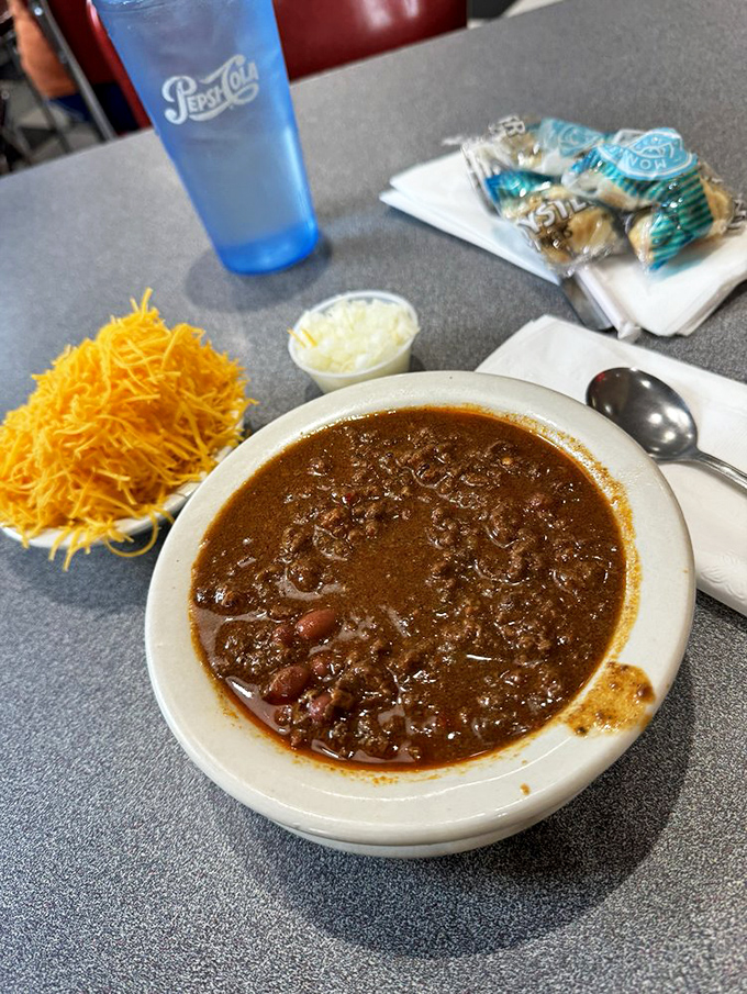 Behold the holy grail of Cincinnati cuisine—a bowl of that distinctive spiced chili with a mountain of cheese waiting patiently on the side.