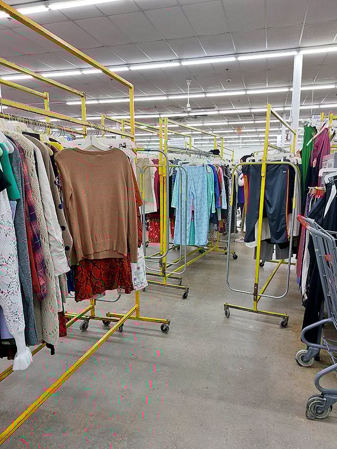 Yellow clothing racks create a golden maze of fashion history, where vintage treasures hide between last season's castoffs.