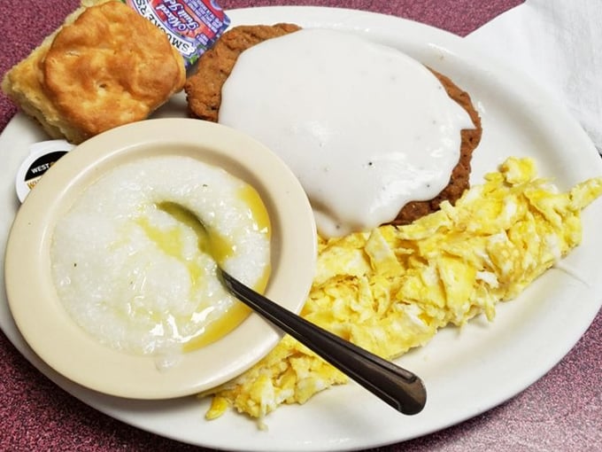 The holy trinity of Southern breakfast: golden country fried steak baptized in gravy, buttery grits, and scrambled eggs that would make any chicken proud.
