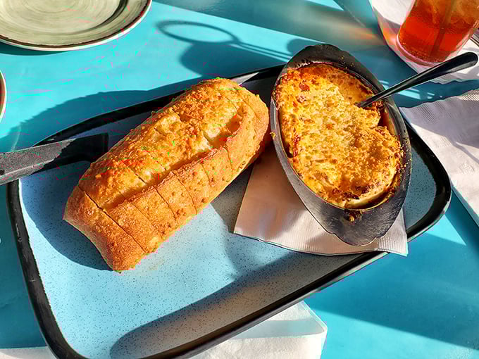 Behold the legendary crab dip, bubbling hot in its cast iron throne, accompanied by slices of toasted baguette standing ready for their noble purpose.