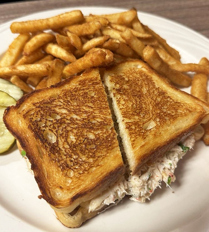 The legendary crab melt arrives like a golden promise: perfectly toasted bread hugging sweet Dungeness crab, with crispy fries standing at attention alongside.
