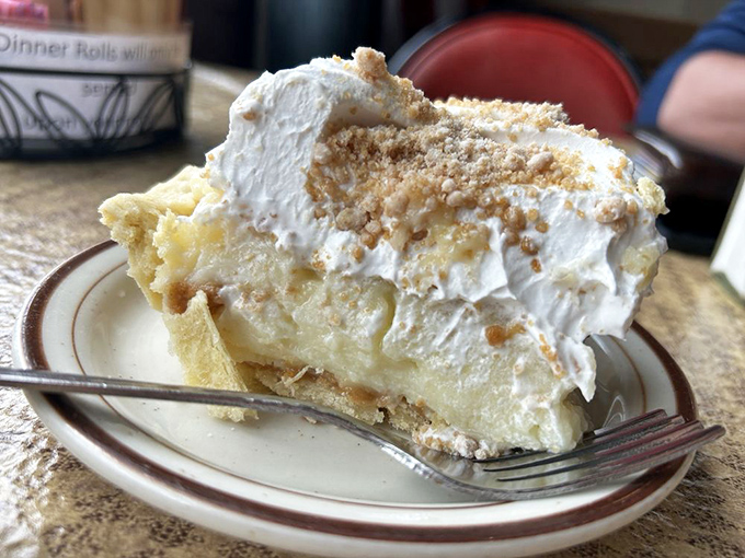 Behold the cream pie in its natural habitat—a mountain of meringue that makes the clouds jealous. This isn't dessert; it's architecture.