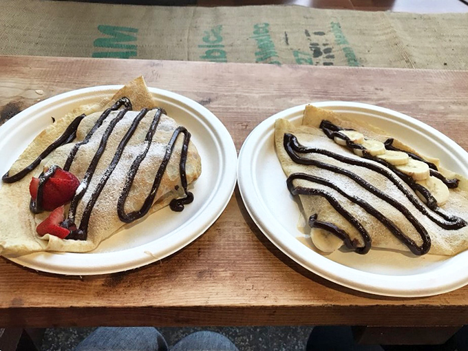 Two crepes, infinite happiness. One strawberry, one banana, both drizzled with chocolate like Jackson Pollock got hungry and decided to paint dessert.