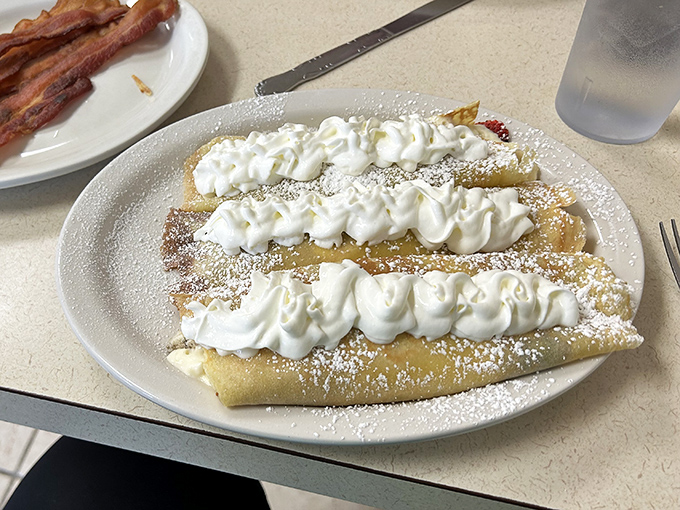 Sweet crepe perfection: golden pancakes crowned with clouds of whipped cream. Dessert masquerading as breakfast, and nobody's complaining.