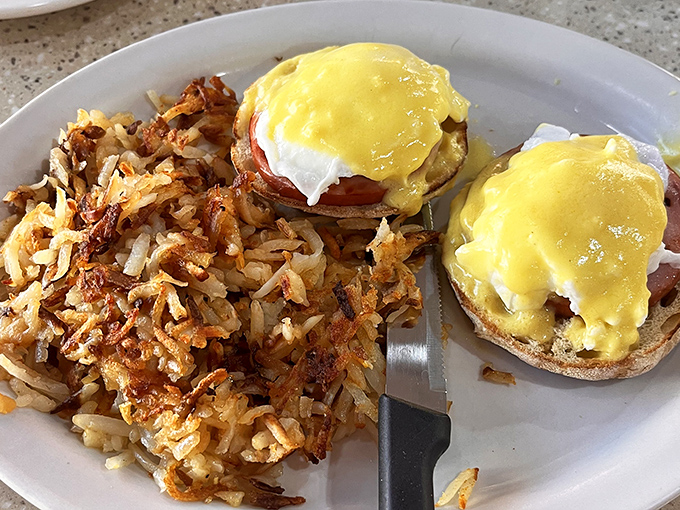 Behold the star attraction! Golden hollandaise cascading over perfectly poached eggs, with crispy hash browns standing by for yolk-soaking duty.