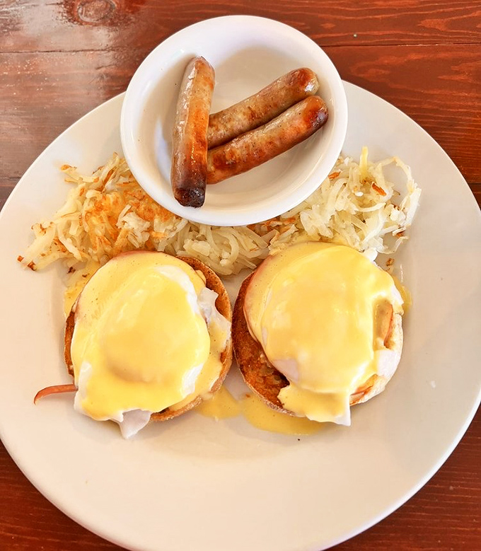 Behold the star of the show! Two perfectly poached eggs draped in sunshine-yellow hollandaise, with crispy hash browns standing guard nearby.