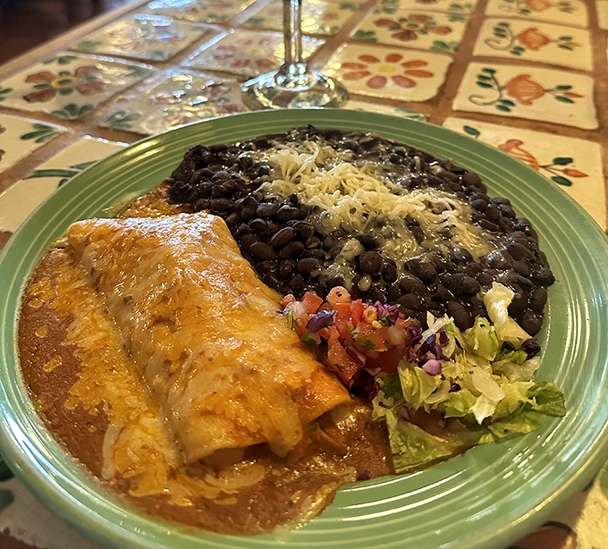 This isn't just an enchilada &ndash; it's a masterclass in comfort food, nestled beside black beans that could make a convert of any legume skeptic.
