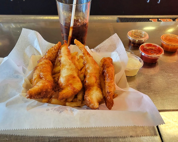 Golden, crispy fish perched atop a bed of fries with dipping sauces standing by. This is what comfort food dreams are made of.