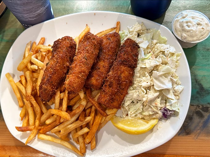 Golden-crusted fish strips lounging on a bed of fries with coleslaw standing guard &ndash; the holy trinity of seafood satisfaction.