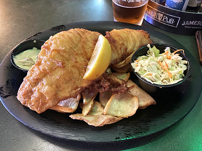 Golden, crispy batter shatters like delicate glass around tender haddock, while a lemon wedge stands ready to cut through the richness &ndash; fish and chips perfection.