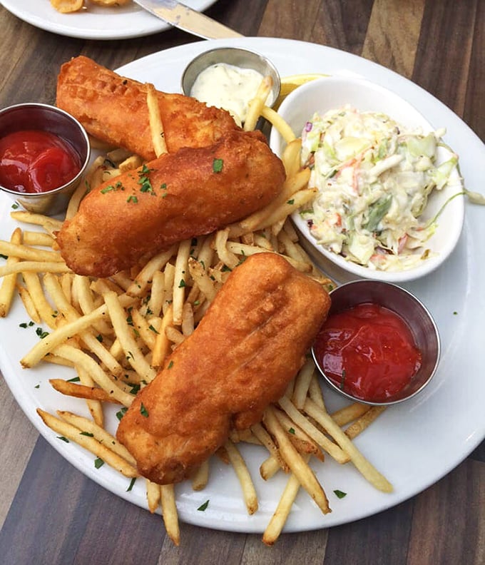 Golden-brown perfection on a plate! The fish and chips arrive with crispy fries, creamy coleslaw, and two dipping sauces for your dunking pleasure.