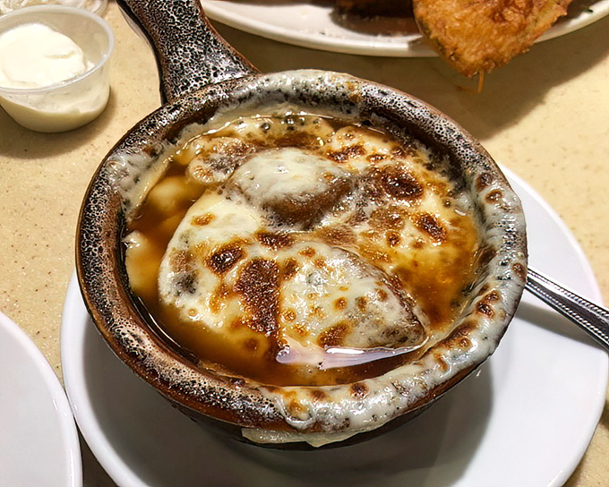 The legendary French onion soup arrives like a bubbling cauldron of joy—cheese stretching to infinity and beyond, making first dates memorably messy since forever.