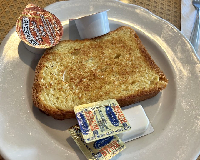 Toast so perfectly golden it belongs in Fort Knox, with butter packets standing by like eager reinforcements ready for deployment.