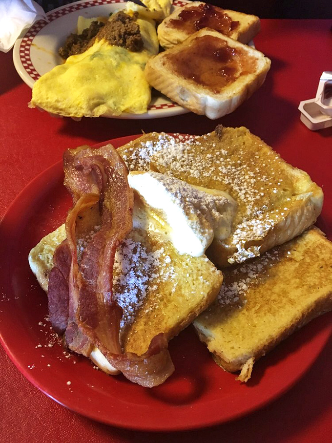 Behold the legendary French toast in all its golden glory, dusted with powdered sugar and accompanied by perfectly crisp bacon—breakfast nirvana achieved.