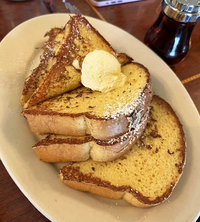 French toast that deserves its own Instagram account—golden, custard-soaked perfection topped with a scoop of butter melting into those crevices of deliciousness.