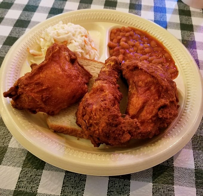 Behold the holy trinity of Southern comfort: spicy fried chicken, creamy coleslaw, and beans that have clearly been simmering since breakfast. Salvation on a paper plate.