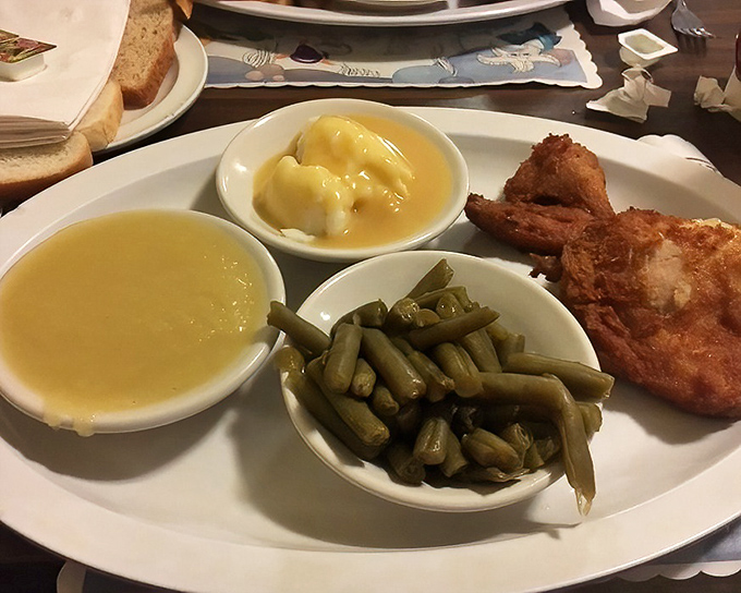 Golden-brown chicken alongside green beans, mashed potatoes, and that signature hot sauce &ndash; a plate that whispers "comfort" but shouts "flavor" with every bite.