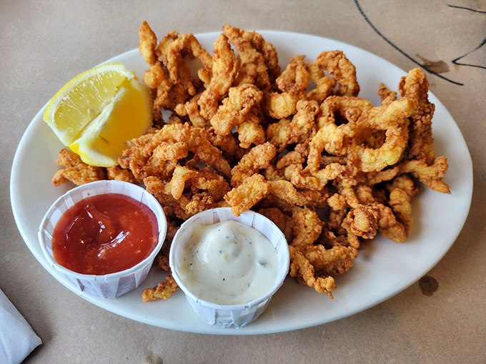 Fried clam strips that crunch like autumn leaves, served with dipping sauces that make you question why you'd ever eat anything else. The perfect golden ratio of crisp to tender.