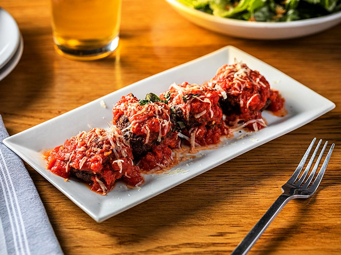 These fried meatballs arrive looking like edible rubies, each one crowned with melted cheese that stretches for days.