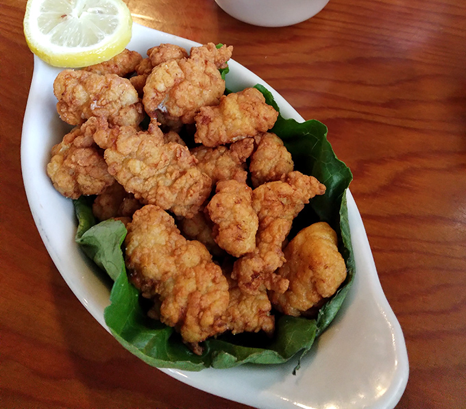 Golden-fried gator tail bites perched on fresh greens &ndash; proof that sometimes the predator becomes the most delicious prey.