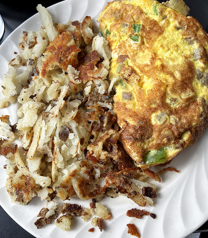 The star of the show: those legendary home fries. Crispy, golden-brown perfection sharing the plate with an omelet that's practically strutting.