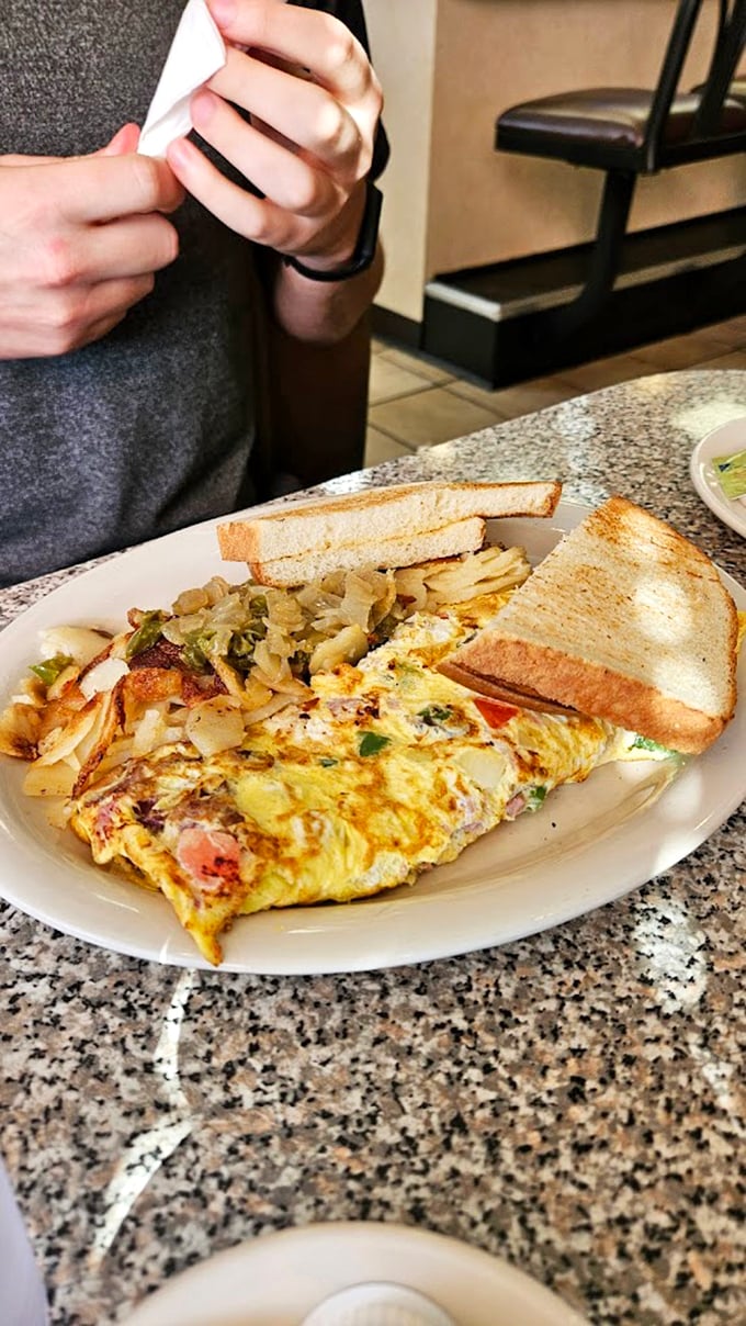This isn't just an omelet&mdash;it's breakfast architecture at its finest, with perfectly folded eggs embracing colorful fillings alongside golden home fries.