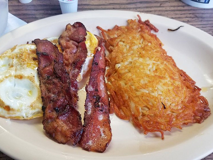 Breakfast perfection on a plate: eggs with edges just crispy enough, bacon that snaps when you bite it, and hash browns that deserve their own fan club.