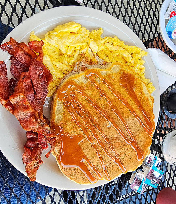 Breakfast nirvana exists, and it looks exactly like this: golden pancakes drizzled with syrup, perfectly scrambled eggs, and bacon that means business.