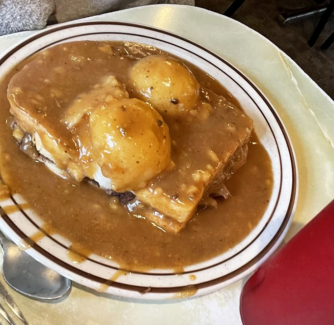 Hot beef sandwich nirvana&mdash;tender bread surrendering to a gravy flood while potatoes stand like delicious islands waiting to be discovered.