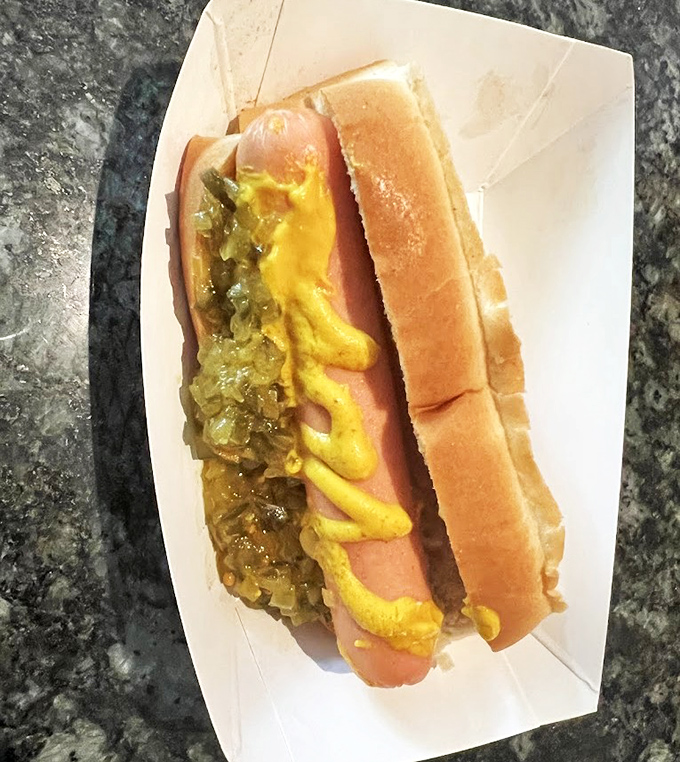 The hot dog arrives like a work of abstract art&mdash;yellow mustard zigzagging across caramelized onions, nestled in a pillowy bun that's seen generations come and go.