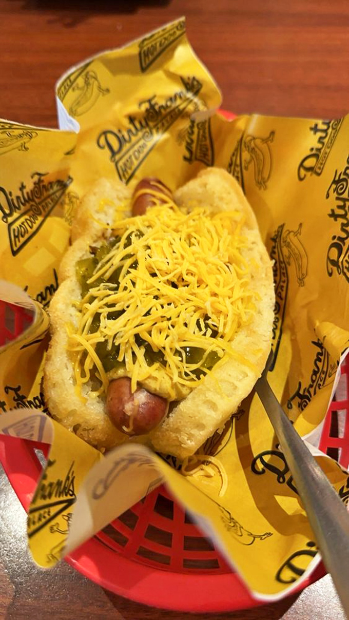 Cheese cascading over a perfectly nestled frank like a yellow waterfall of joy. This isn't just lunch&mdash;it's edible happiness wrapped in branded paper. 