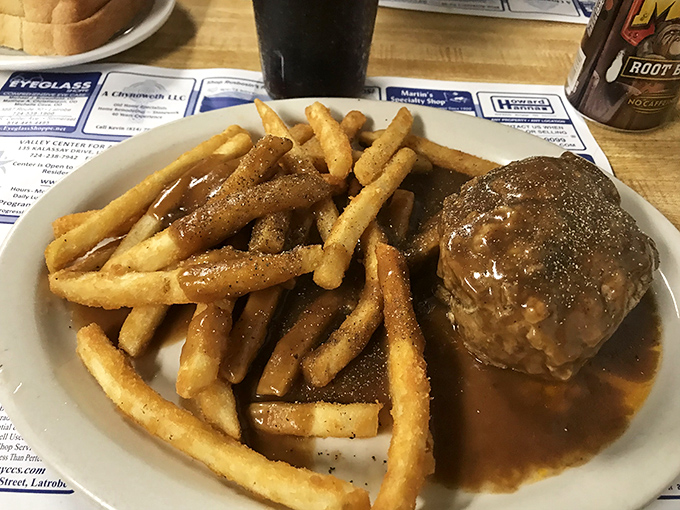 The legendary hot hamburger steak in all its glory – a hand-formed patty swimming in rich gravy that transforms ordinary fries into flavor sponges.