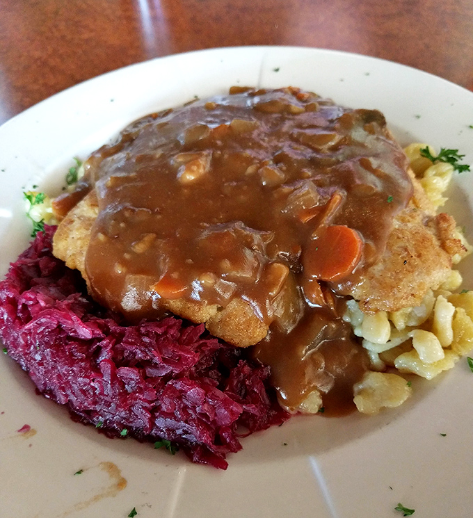 The legendary Jagerschnitzel in its natural habitat &ndash; swimming in mushroom gravy alongside vibrant red cabbage that could convert any cabbage skeptic.