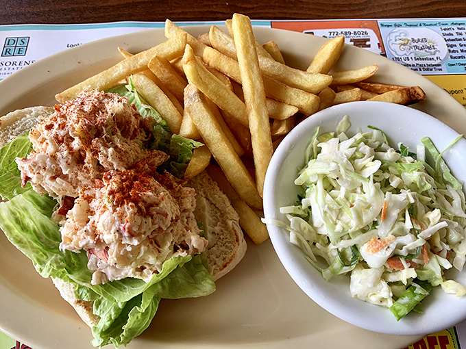 The legendary lobster roll arrives like Neptune's gift – chunky seafood treasure nestled on a bed of lettuce, flanked by golden fries and fresh coleslaw.