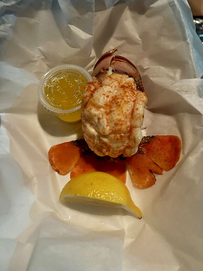 This lobster tail isn't just food&mdash;it's a crustacean celebration on parchment paper. The drawn butter stands by like liquid gold awaiting its moment.