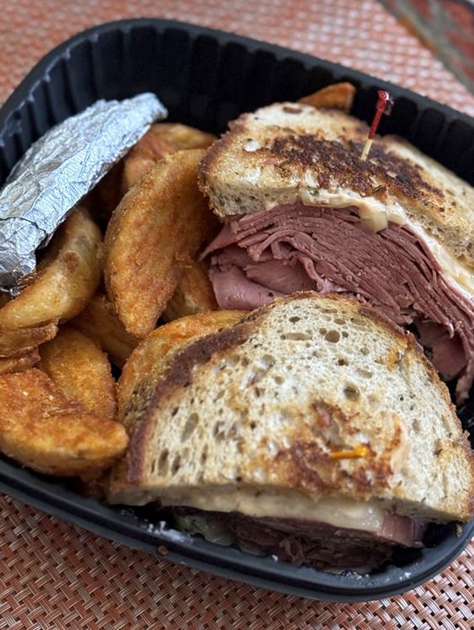 This isn't just a sandwich; it's a skyscraper of corned beef with melted cheese as the penthouse. The onion rings are just showing off at this point.