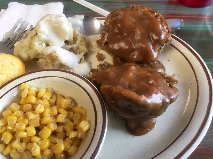 Two glorious slices of meatloaf swimming in gravy, flanked by mashed potatoes and corn like edible bodyguards.