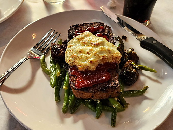That meatloaf sits on its vegetable throne like royalty, topped with what appears to be bleu cheese magnificence.