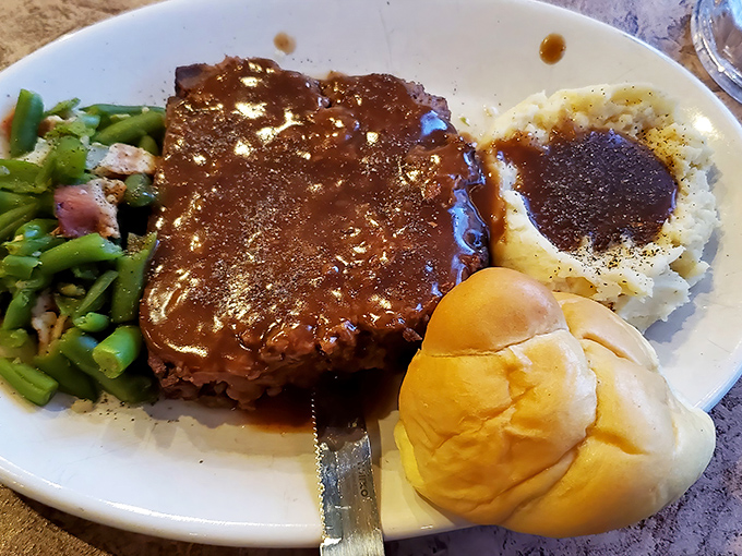 Behold the star attraction: homemade meatloaf swimming in savory gravy alongside green beans and mashed potatoes. Grandma would approve!