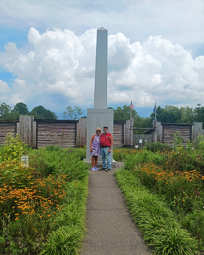 A moment of historical reverence amid vibrant gardens. This monument stands tall against Kentucky's cloud-dotted sky, honoring those who blazed the original trails.