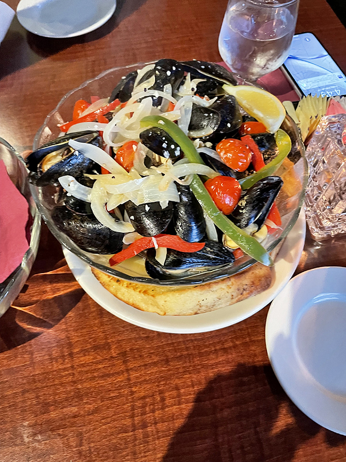 These mussels aren't just served—they're presented like edible art. Plump shellfish bathed in a colorful medley of peppers and onions atop toasted bread.