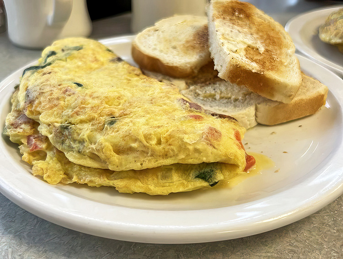 Behold the holy grail of breakfast—a perfectly executed omelet alongside golden toast. This fluffy egg masterpiece is worth crossing county lines for.