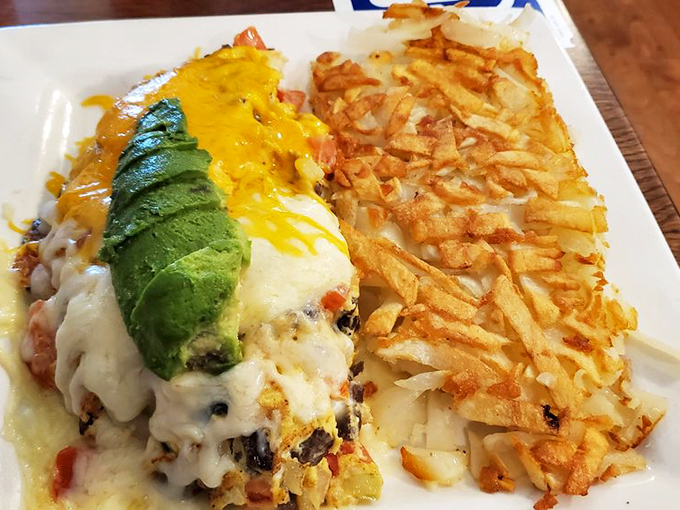 Behold the star of our show: a perfectly executed omelet crowned with avocado and melted cheese, with hash browns that deserve their own fan club.