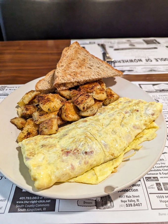 Behold the omelet in its natural habitat – fluffy, generously filled, and accompanied by home fries that deserve their own fan club.