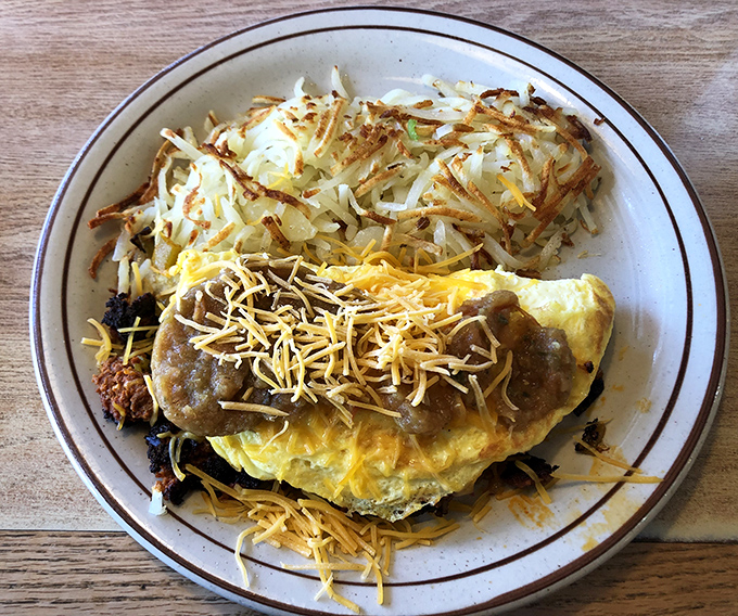 This isn't just an omelet &ndash; it's a masterpiece of morning engineering with perfectly melted cheese and crispy hash browns standing guard.