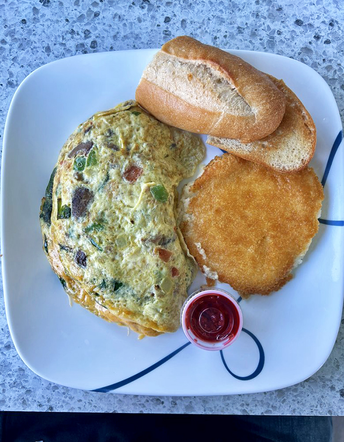 This isn't just an omelet; it's a masterclass in egg architecture&mdash;perfectly folded around vibrant veggies with a hash brown sidekick that deserves its own fan club.