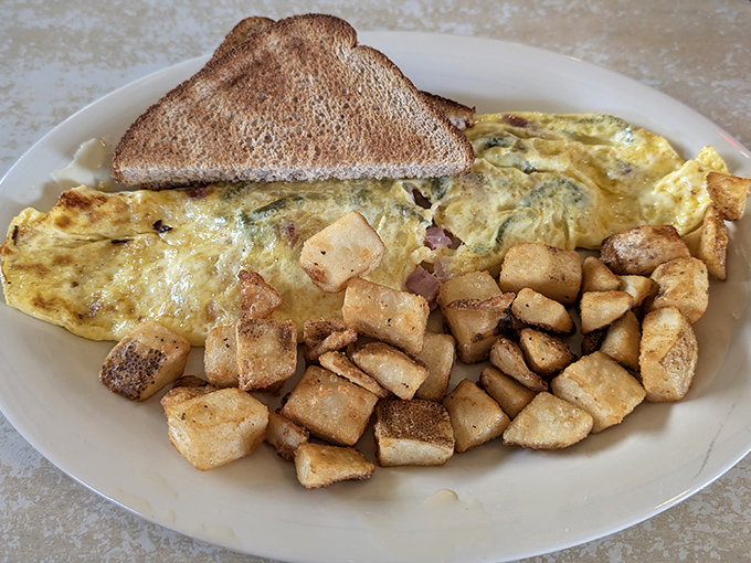 Behold the omelet that launched a thousand road trips! Perfectly folded with those home fries looking like they've earned PhDs in crispiness.